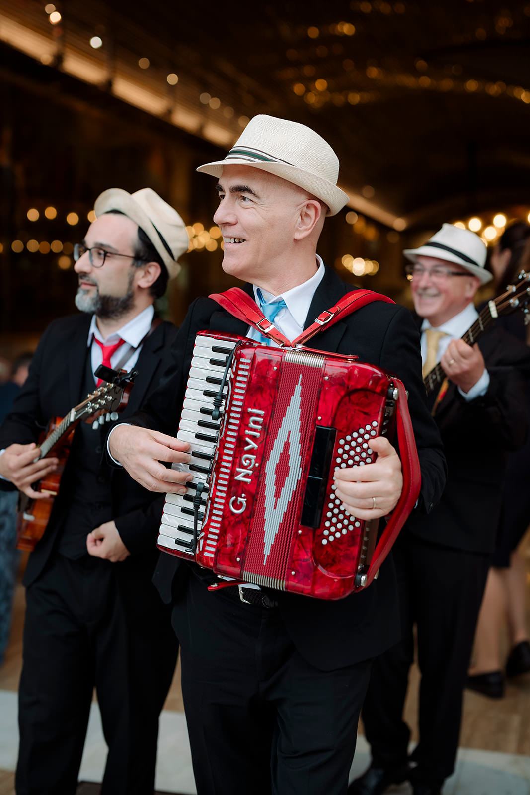 Three musicians in suits and hats perform joyfully at a destination ...