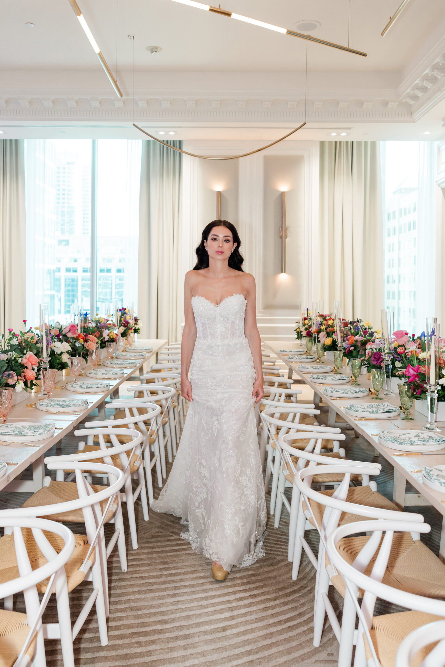 A woman in a strapless white lace wedding gown stands between two ...
