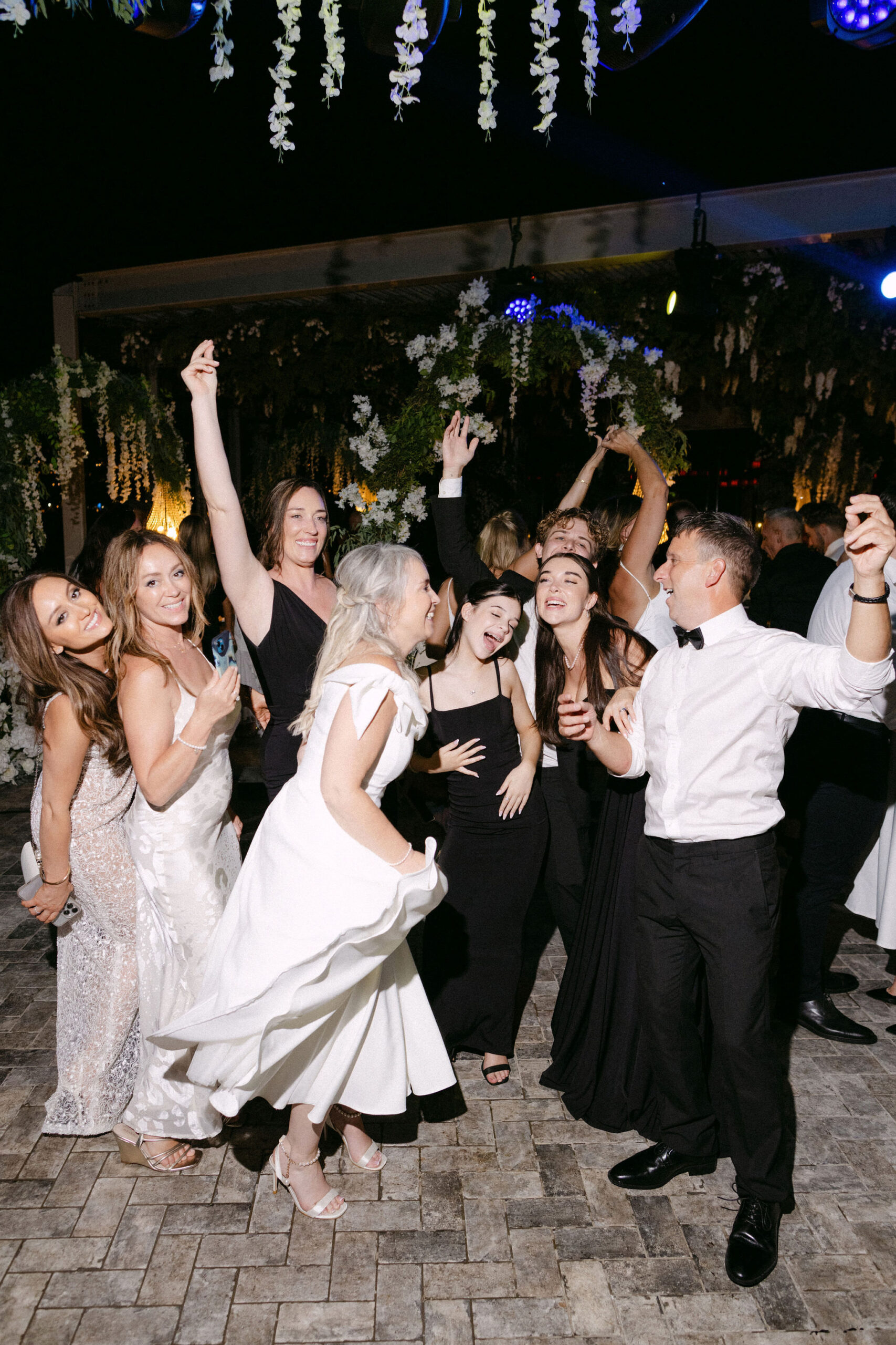 A group of people dressed in formal attire joyfully dance and celebrate ...