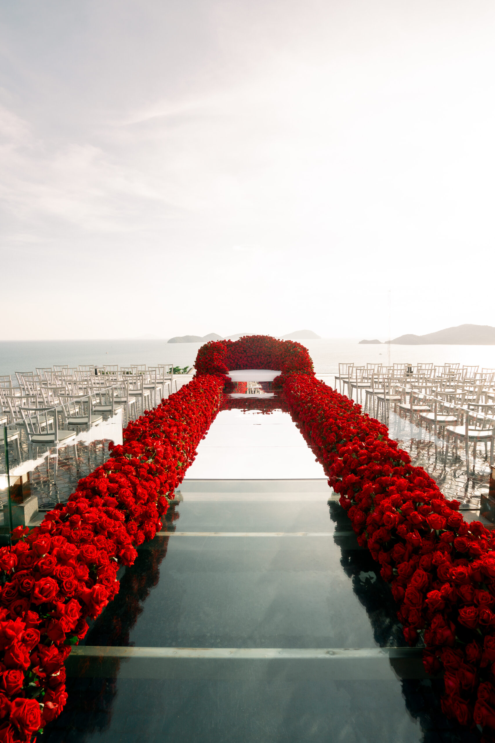 A stunning red rose wedding aisle leads to an elegant archway, flanked ...