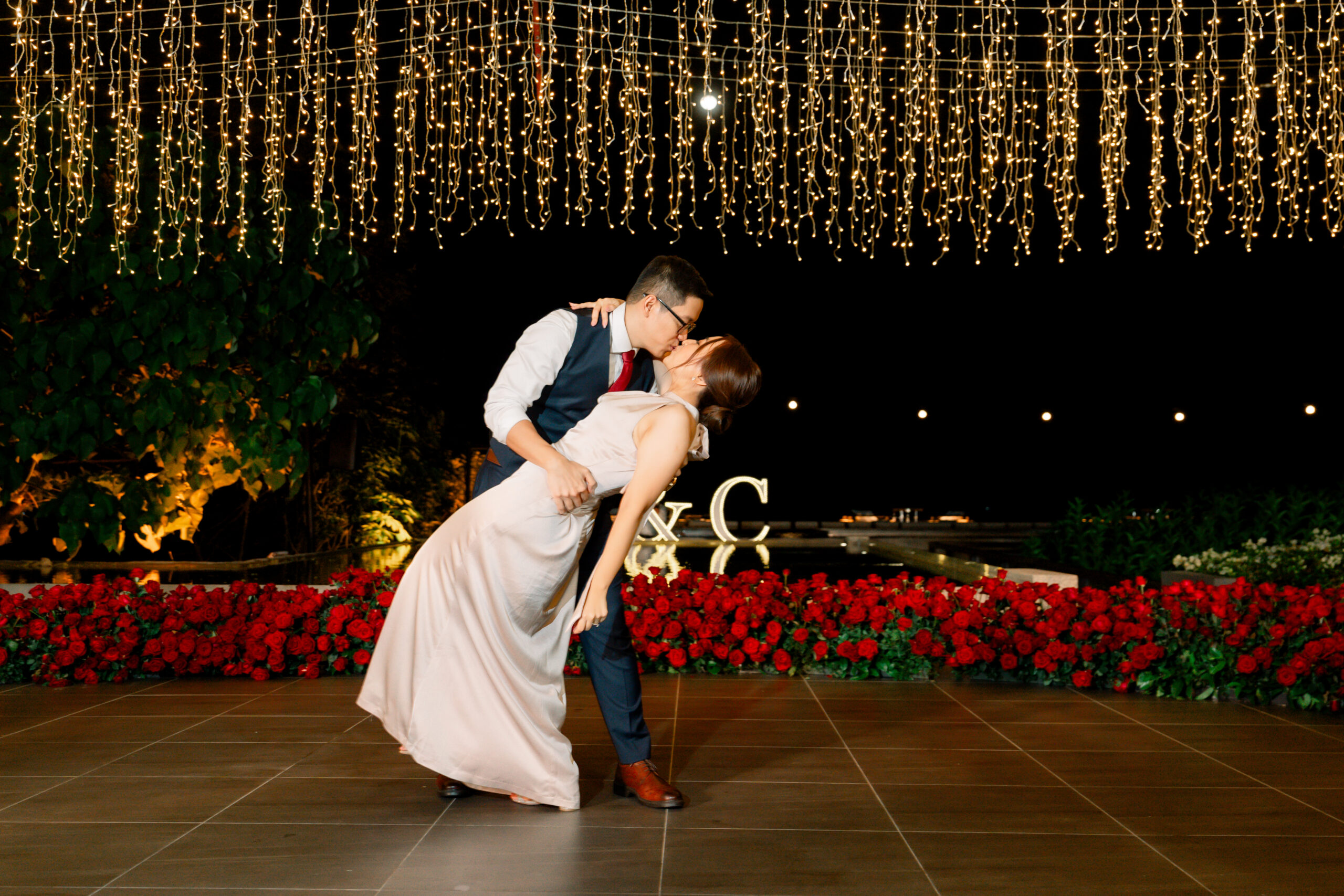 A couple dressed in formal attire shares a romantic dip and kiss on the ...