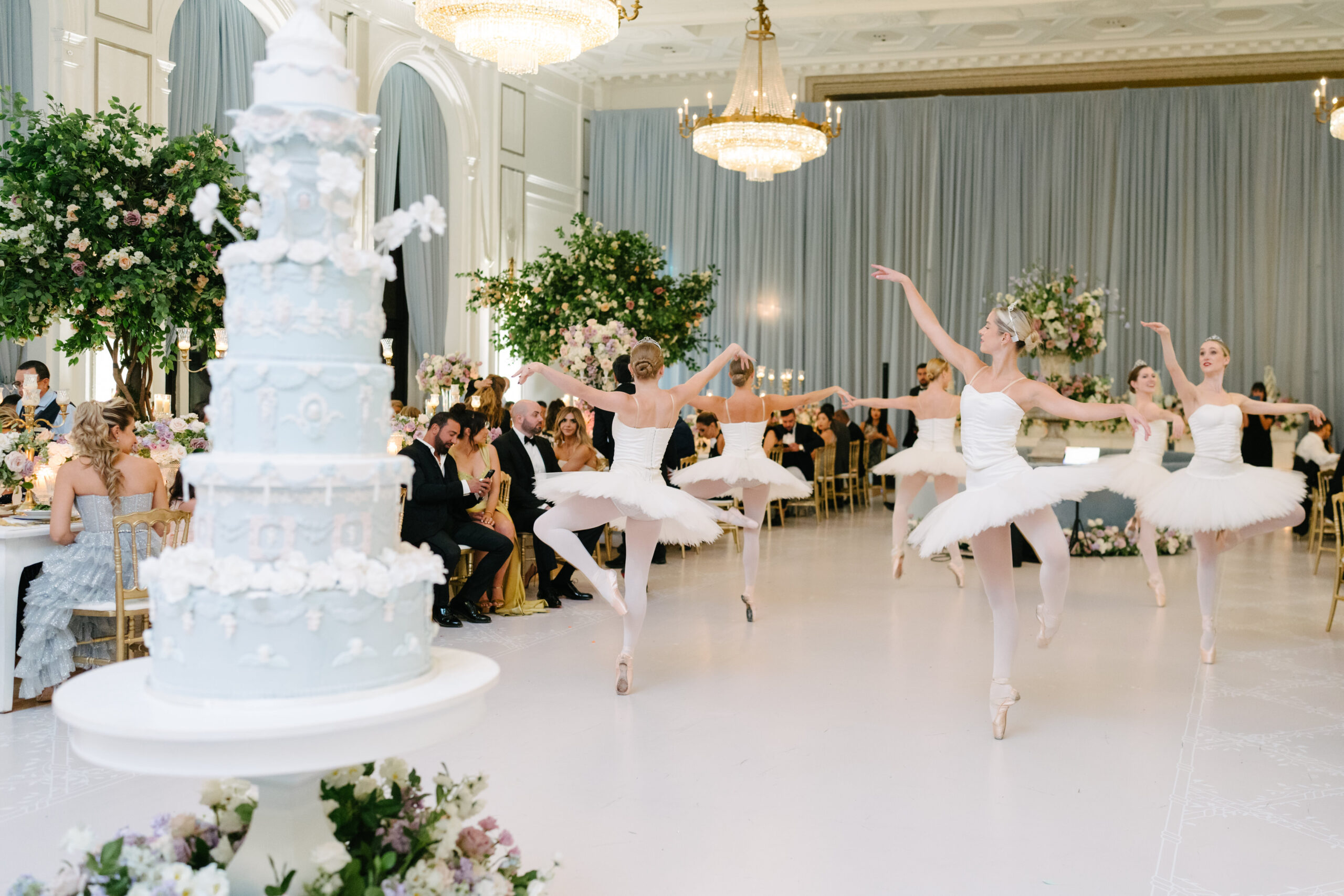 A group of ballerinas in white tutus perform in a grand ballroom at the ...