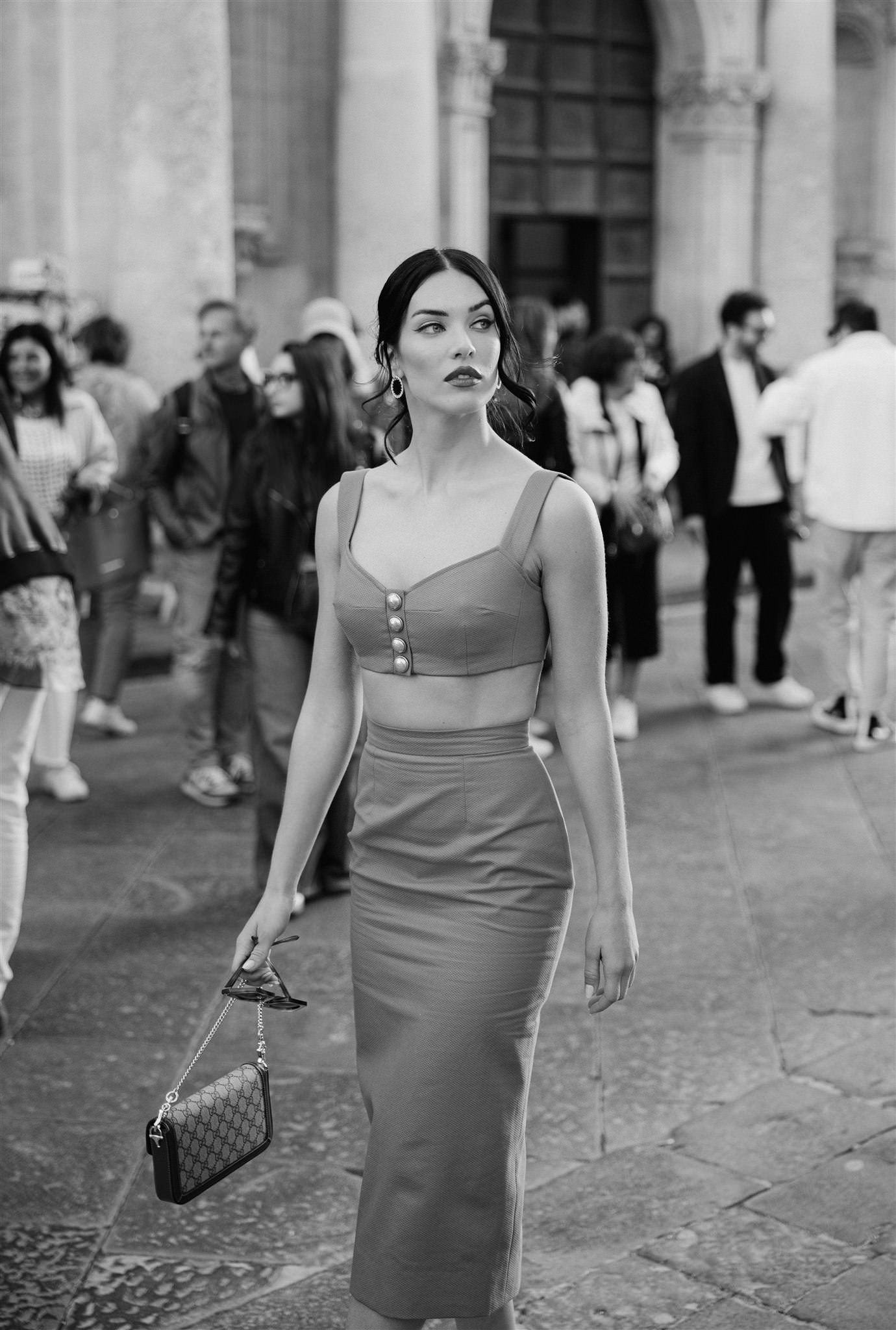 A woman in a fitted, buttoned crop top and matching high-waisted skirt ...