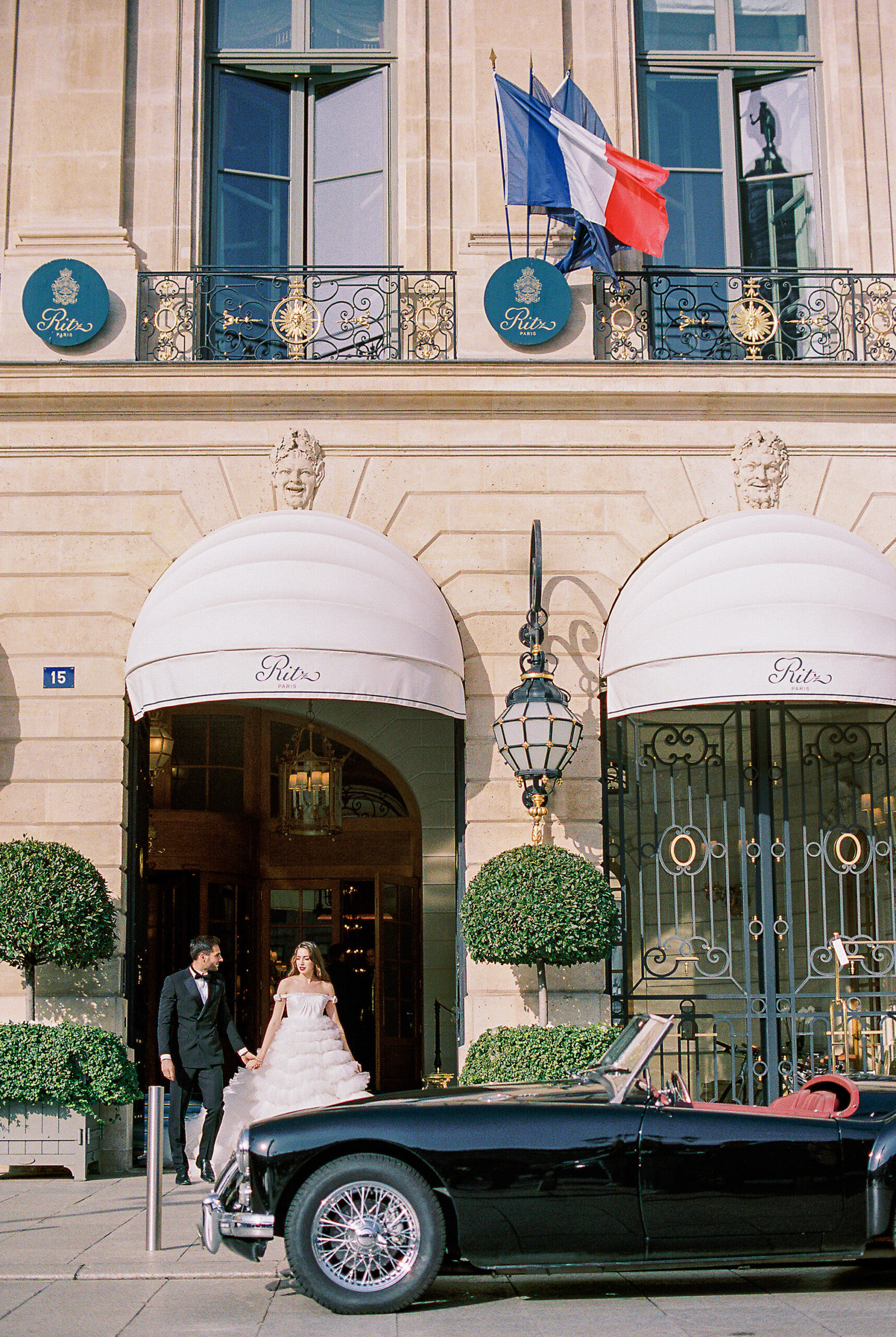 A bride and groom hold hands outside the Ritz Paris, standing near a ...