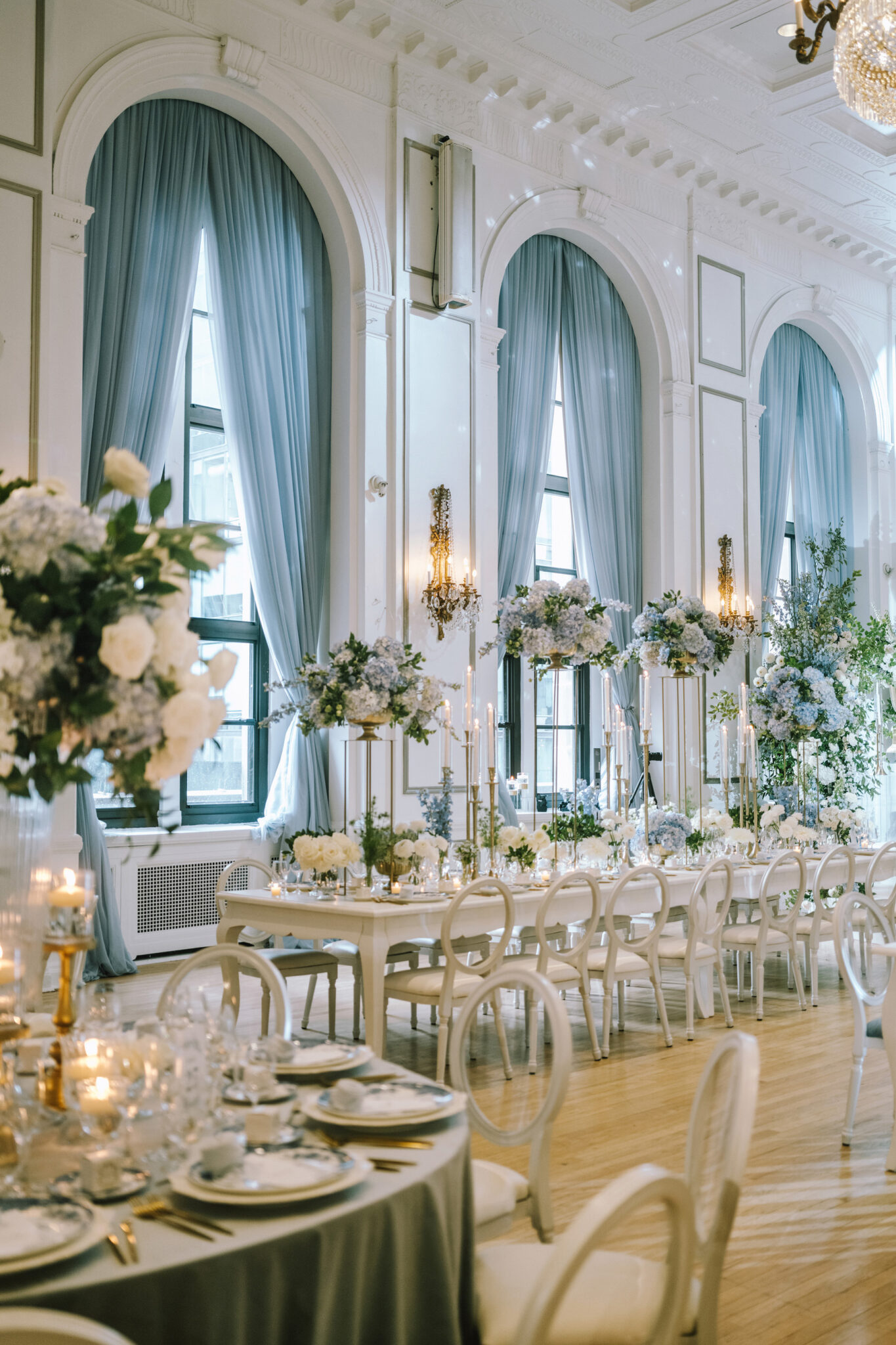 Elegant ballroom with tall arched windows and blue drapes, lavishly ...
