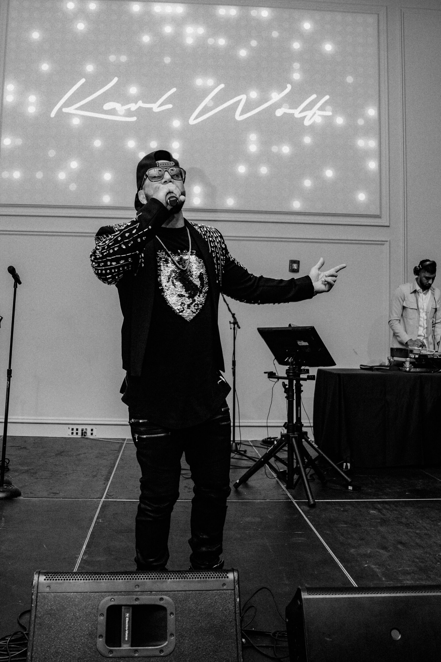 A performer wearing sunglasses and a jeweled jacket sings into a ...
