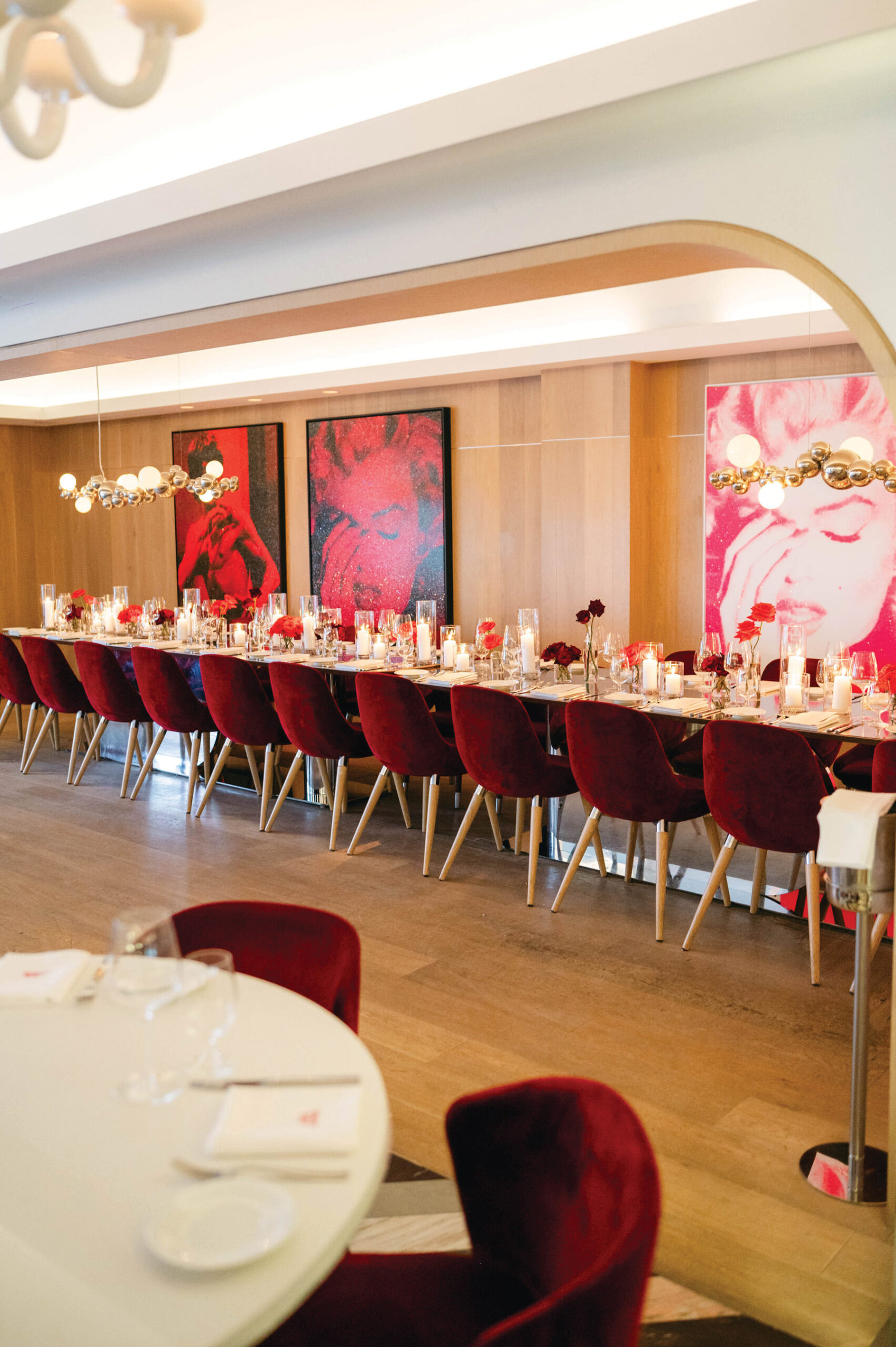 A long dining table with red velvet chairs, set for an Editorially ...