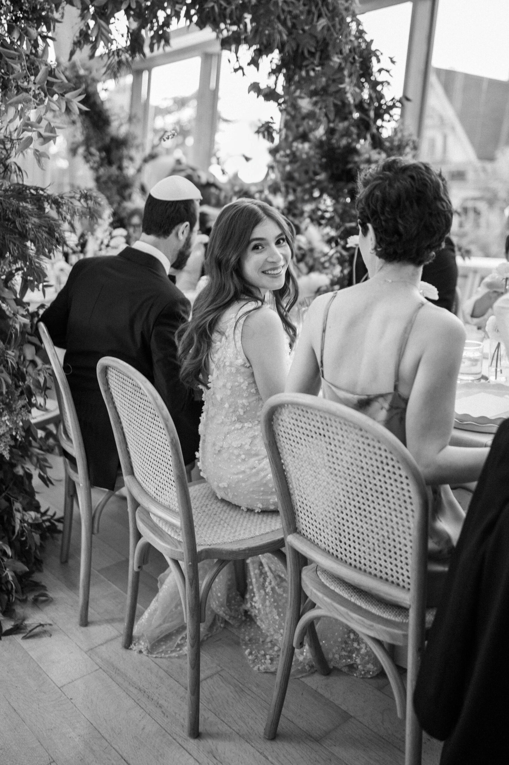 A woman in a sequined dress smiles at the camera while seated at a ...