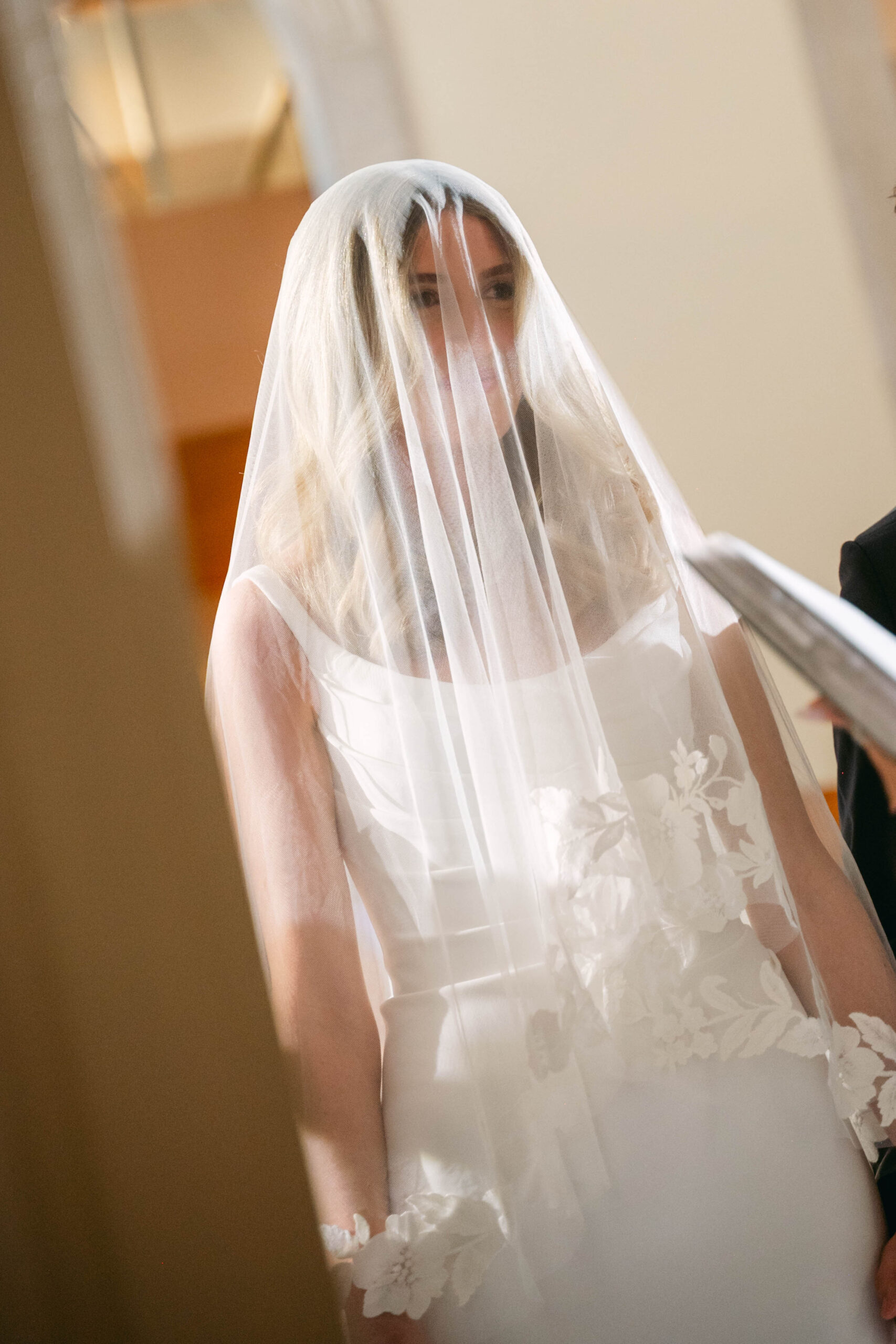 A bride in a white dress and floral veil stands indoors at the Art ...