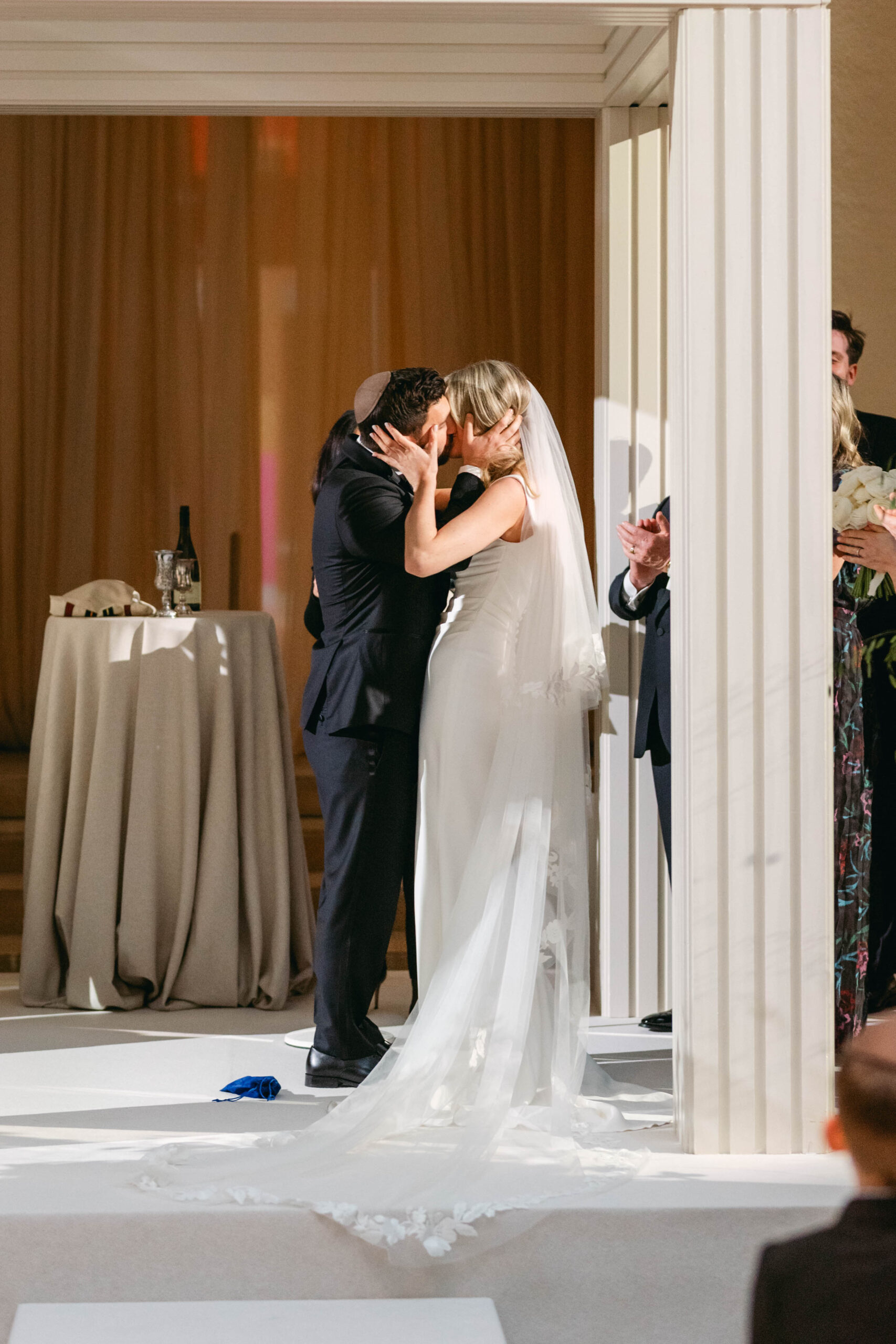 A bride and groom share a kiss at their modern wedding ceremony under a ...