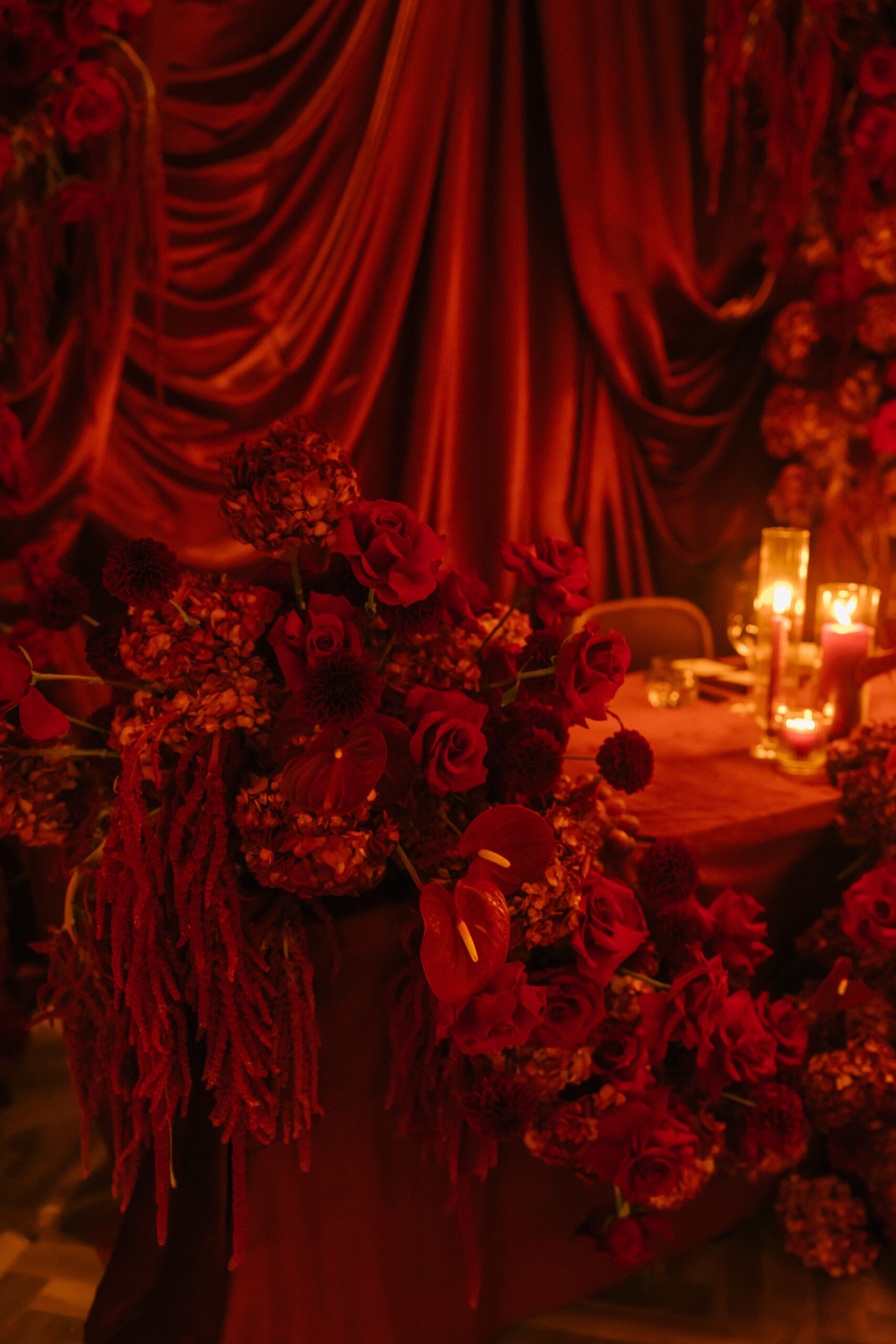 A lavishly decorated table with deep red flowers, including roses and ...