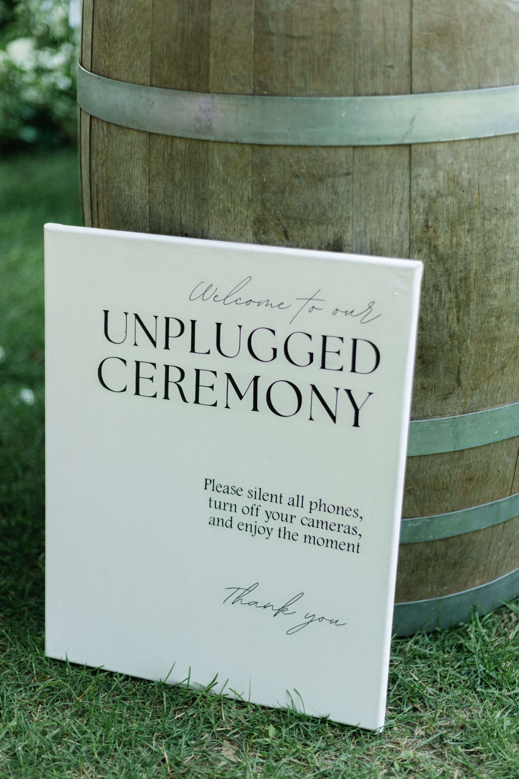 A white sign at a dreamy summer tent wedding leans against a wooden ...