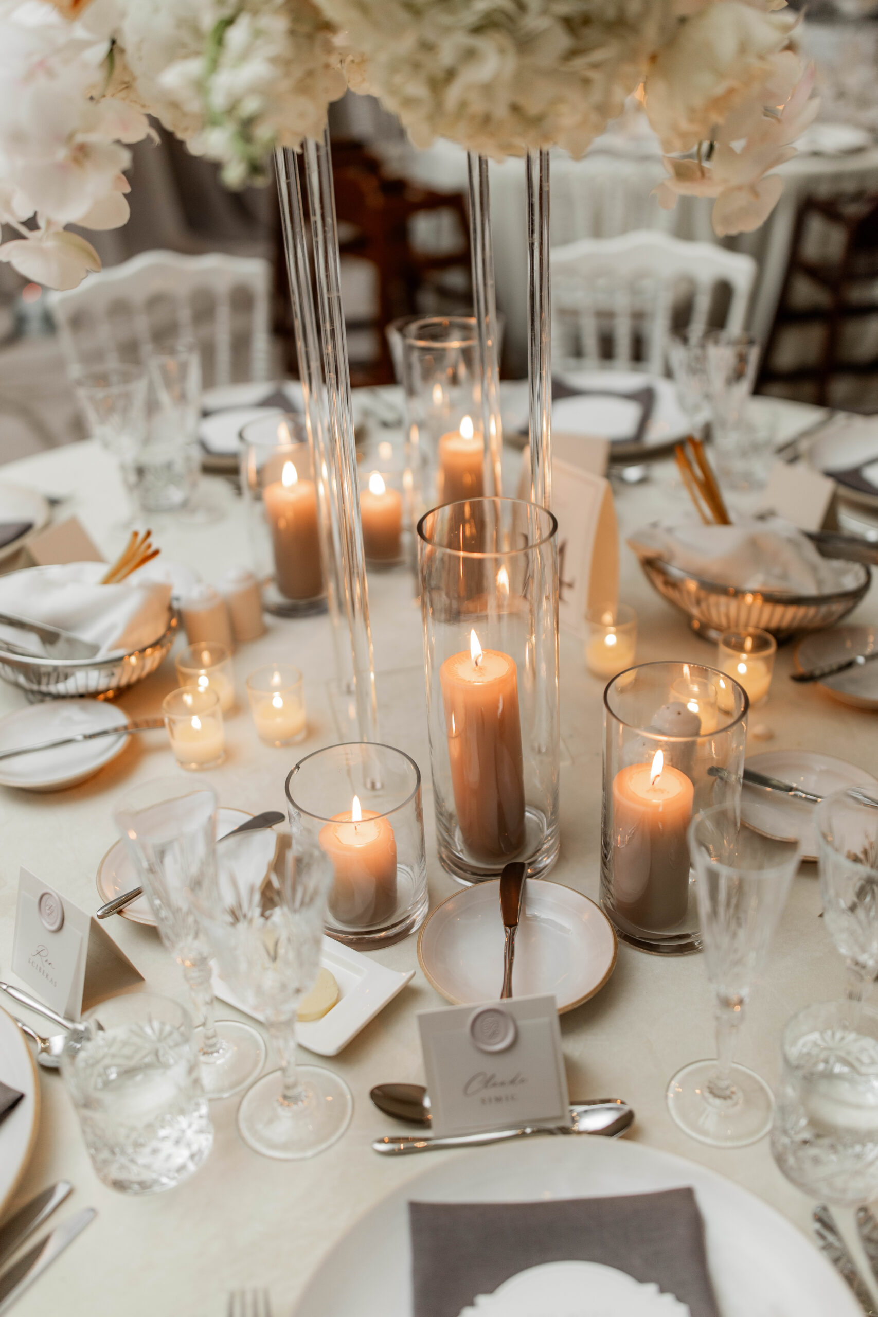 Elegant table setting with tall glass vases holding lit candles ...