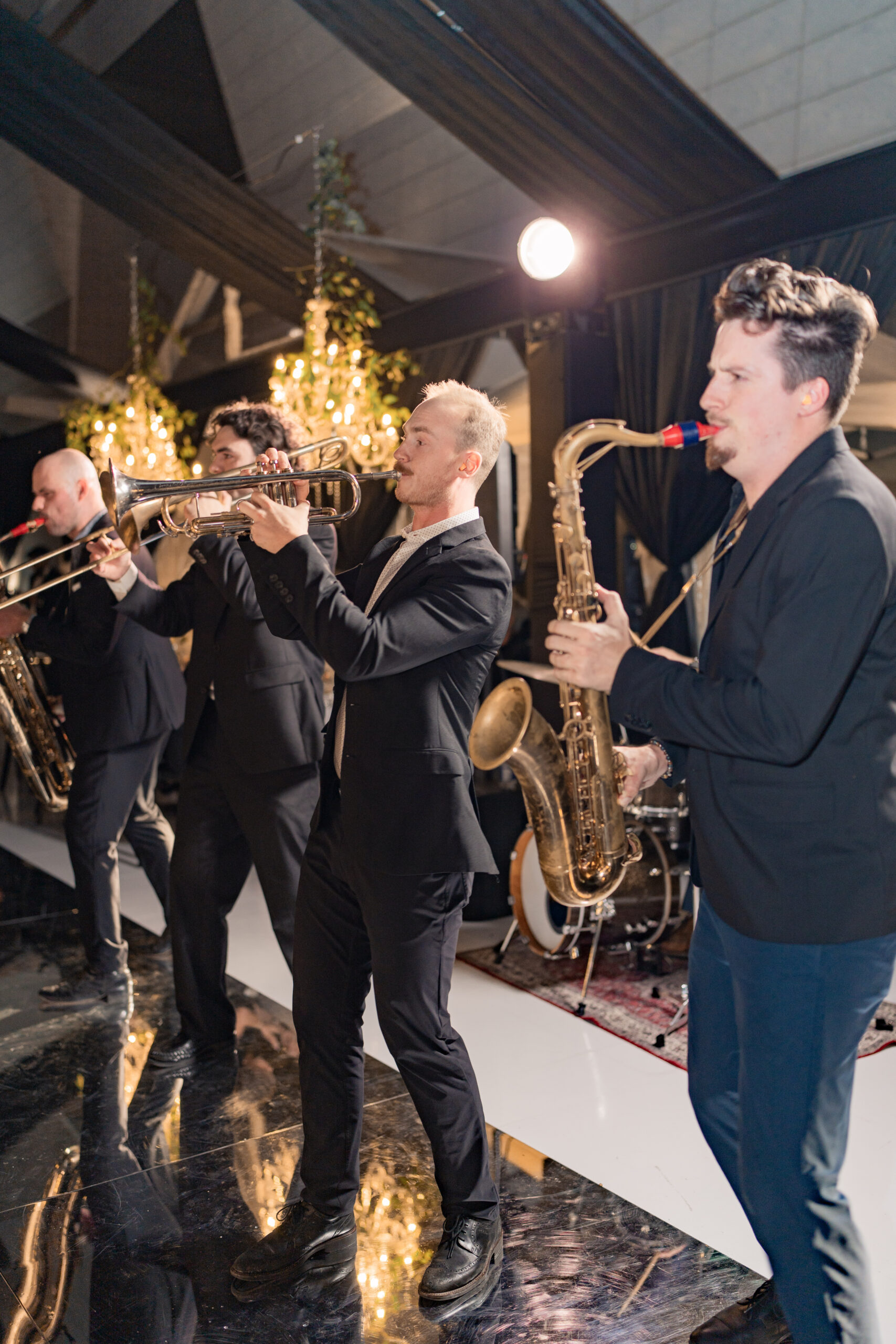 A group of musicians in black suits play brass instruments, including ...