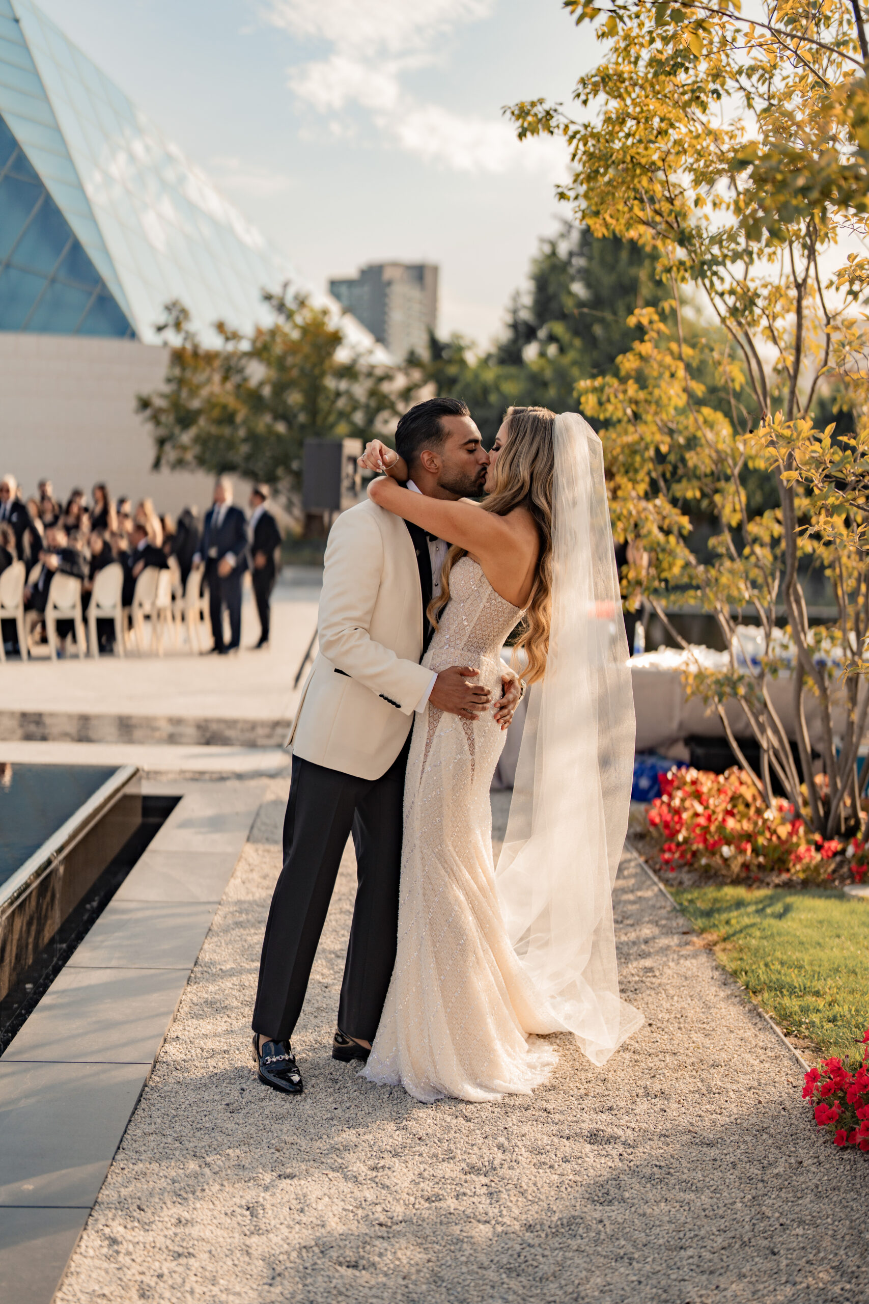 A bride and groom kiss outdoors during their Aga Khan Museum pavilion ...