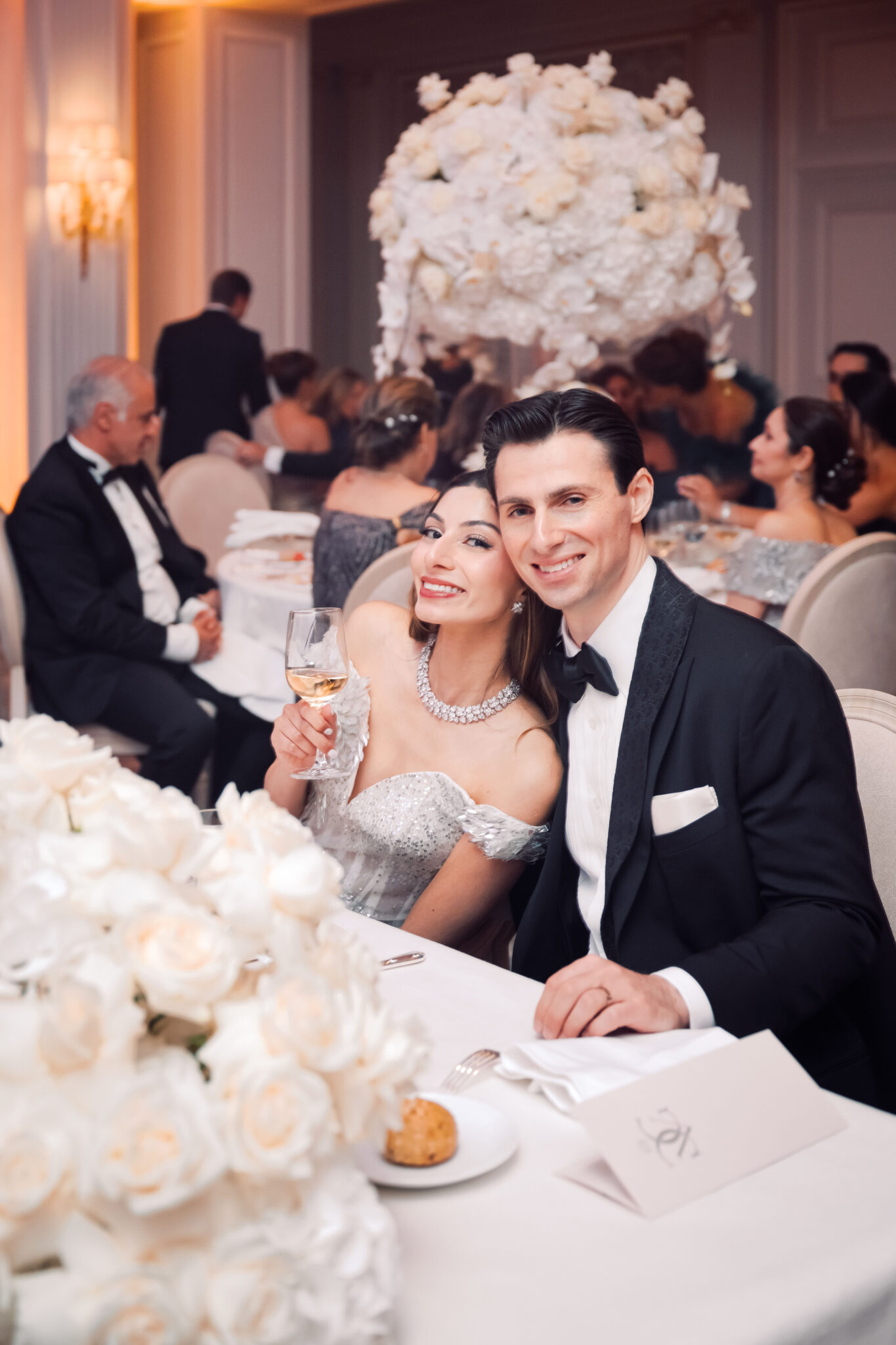 A smiling couple in formal attire sits at an elegantly decorated table ...