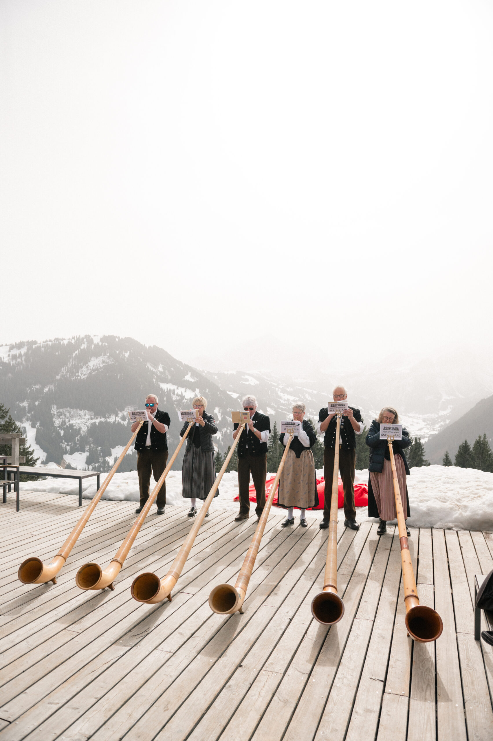 A group of people in traditional clothing play long wooden alphorns on ...