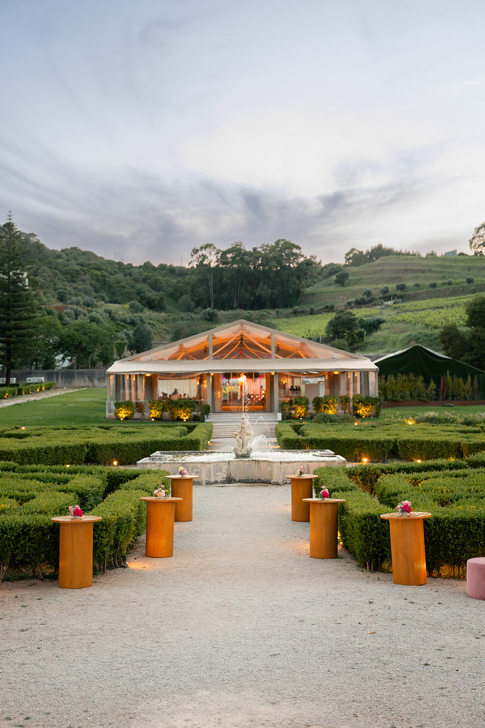 A garden pathway with neatly trimmed hedges leads to a gazebo draped in ...