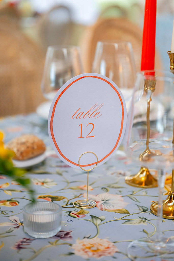 A table number sign reading "table 12" in orange script stands on a ...